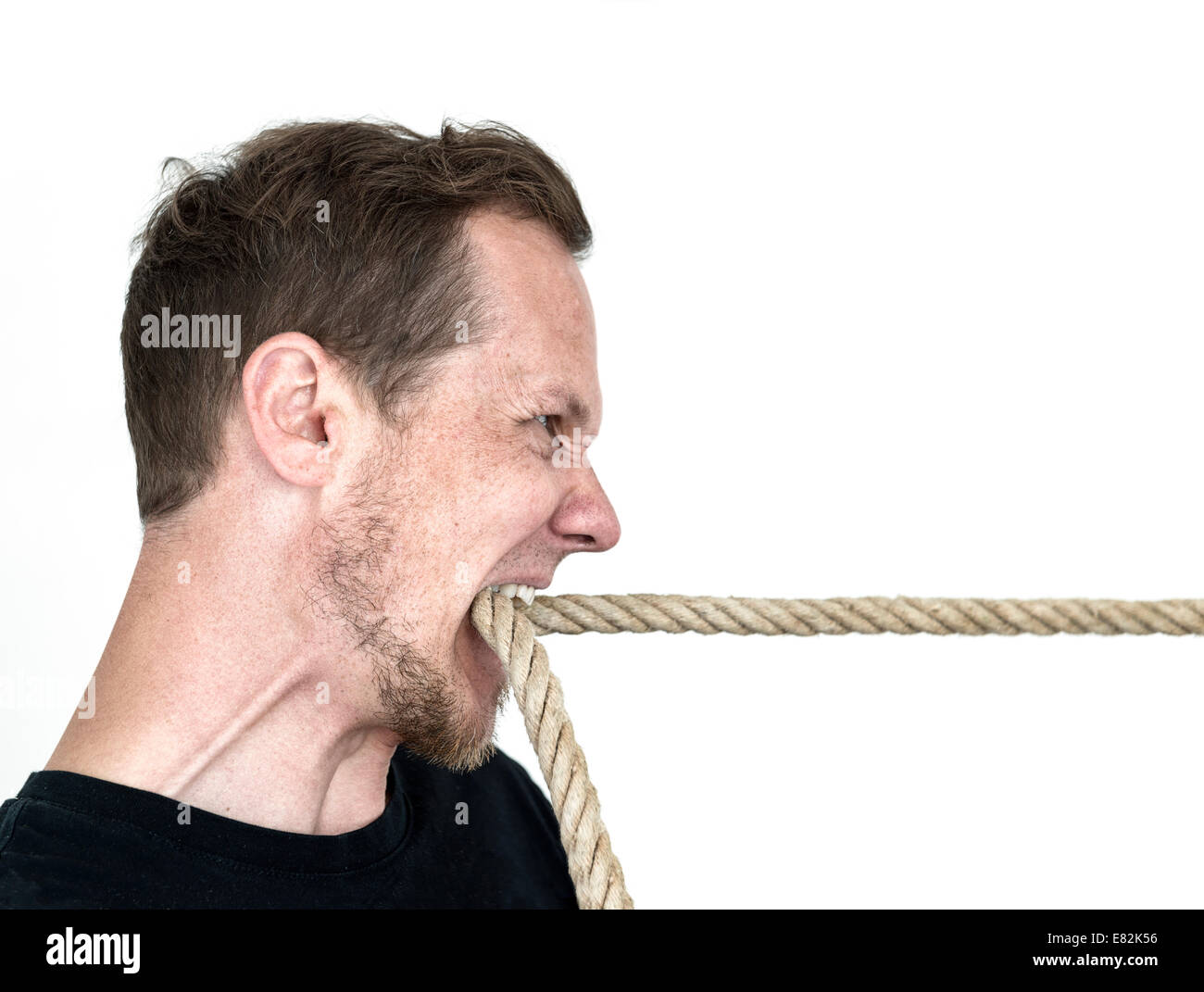 Mann pulling a rope by the teeth Stock Photo - Alamy