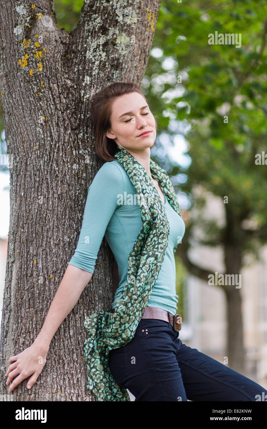 Woman leaning against a tree Stock Photo - Alamy