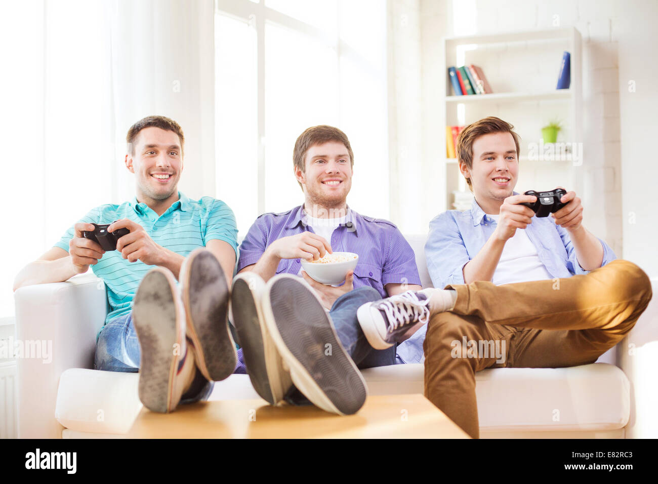 smiling friends playing video games at home Stock Photo - Alamy