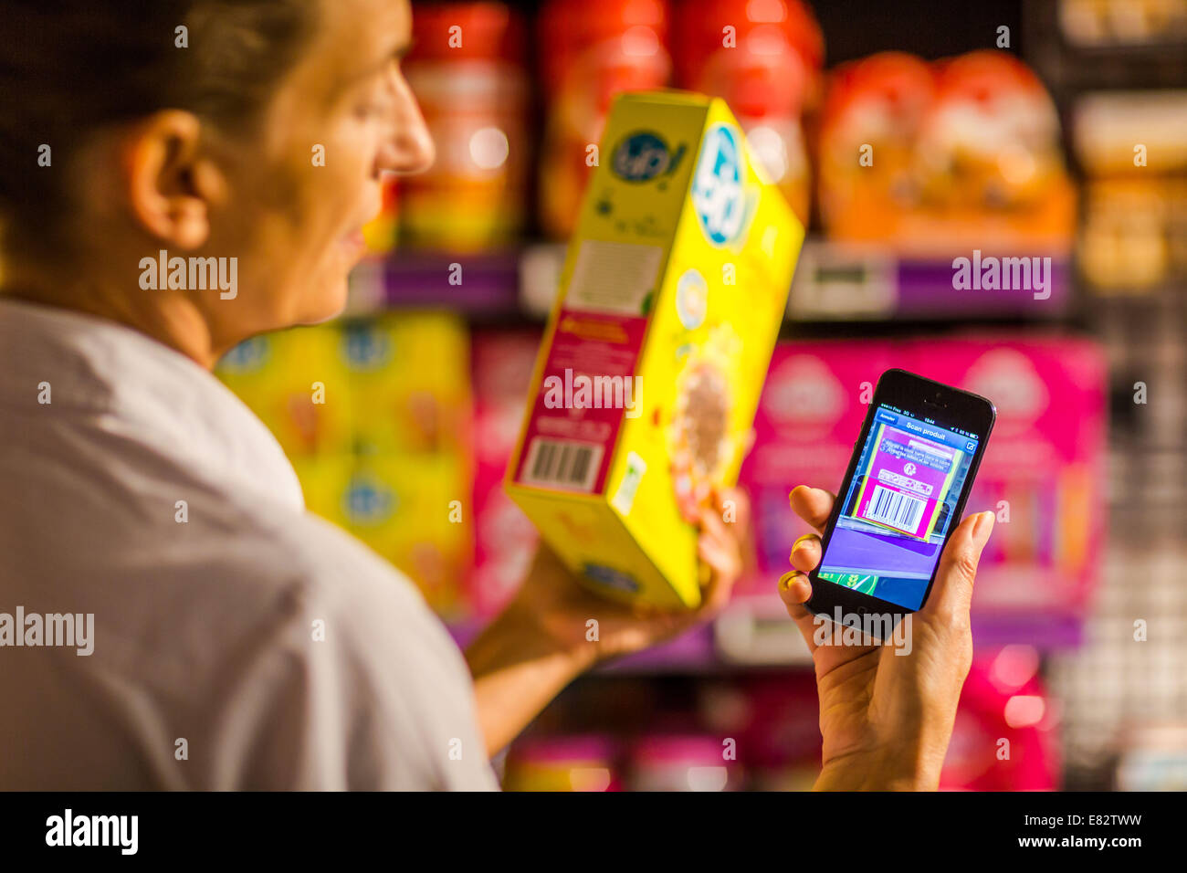Woman using a smartphone in supermarket Stock Photo - Alamy