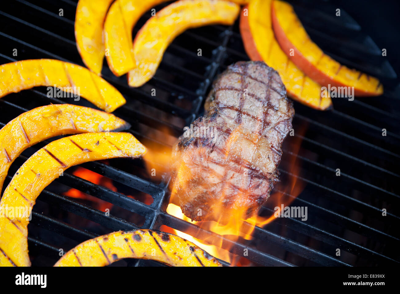 Flame stroking a rib eye steak and slices of Hokkaido pumpkin on the ...