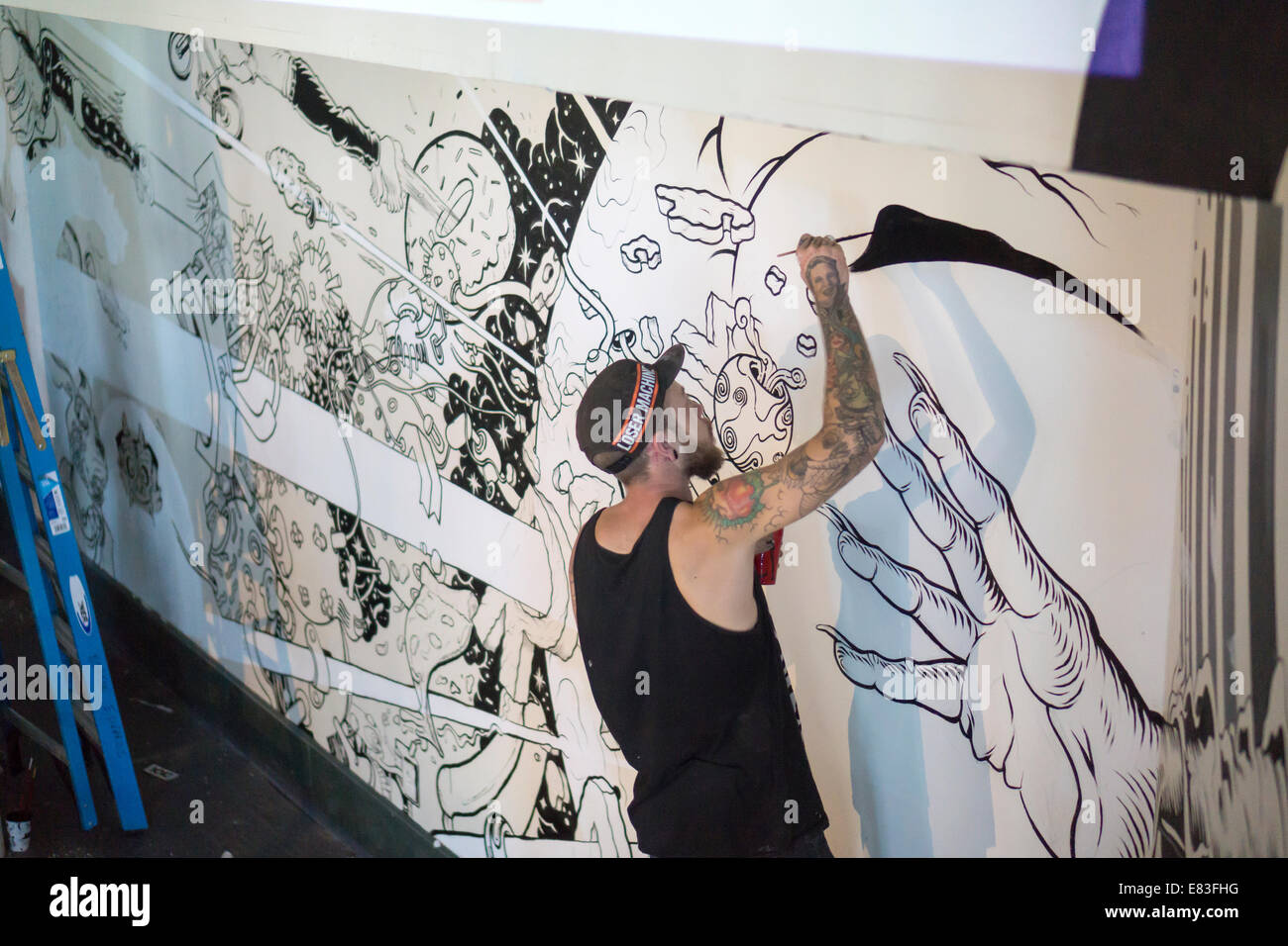 An artist from the En Masse Collective paints a mural in the Brooklyn ...
