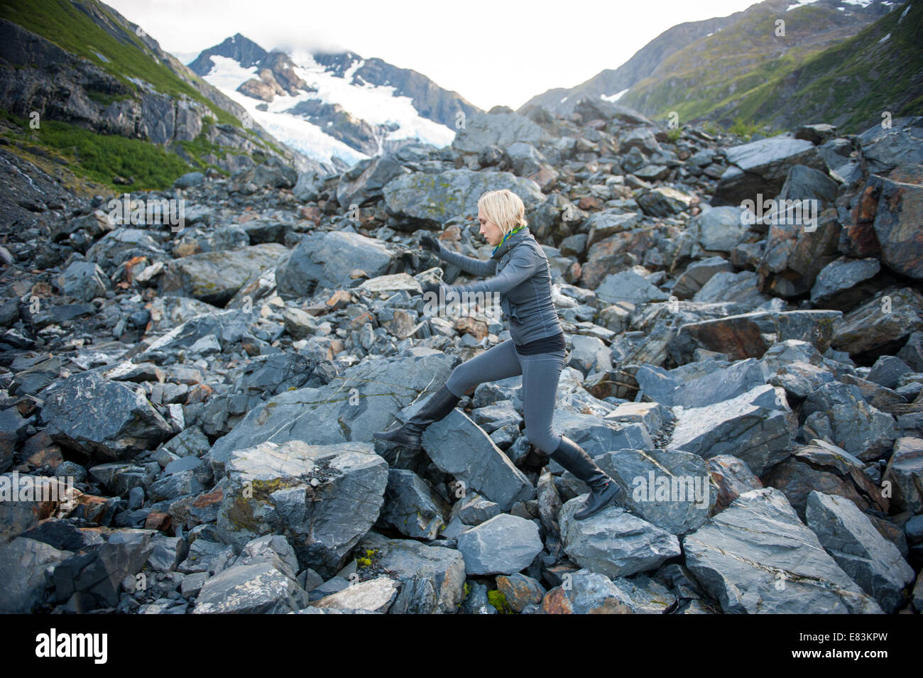 Woman scrambling over rocks by Byron Glacier Alaska Stock Photo - Alamy