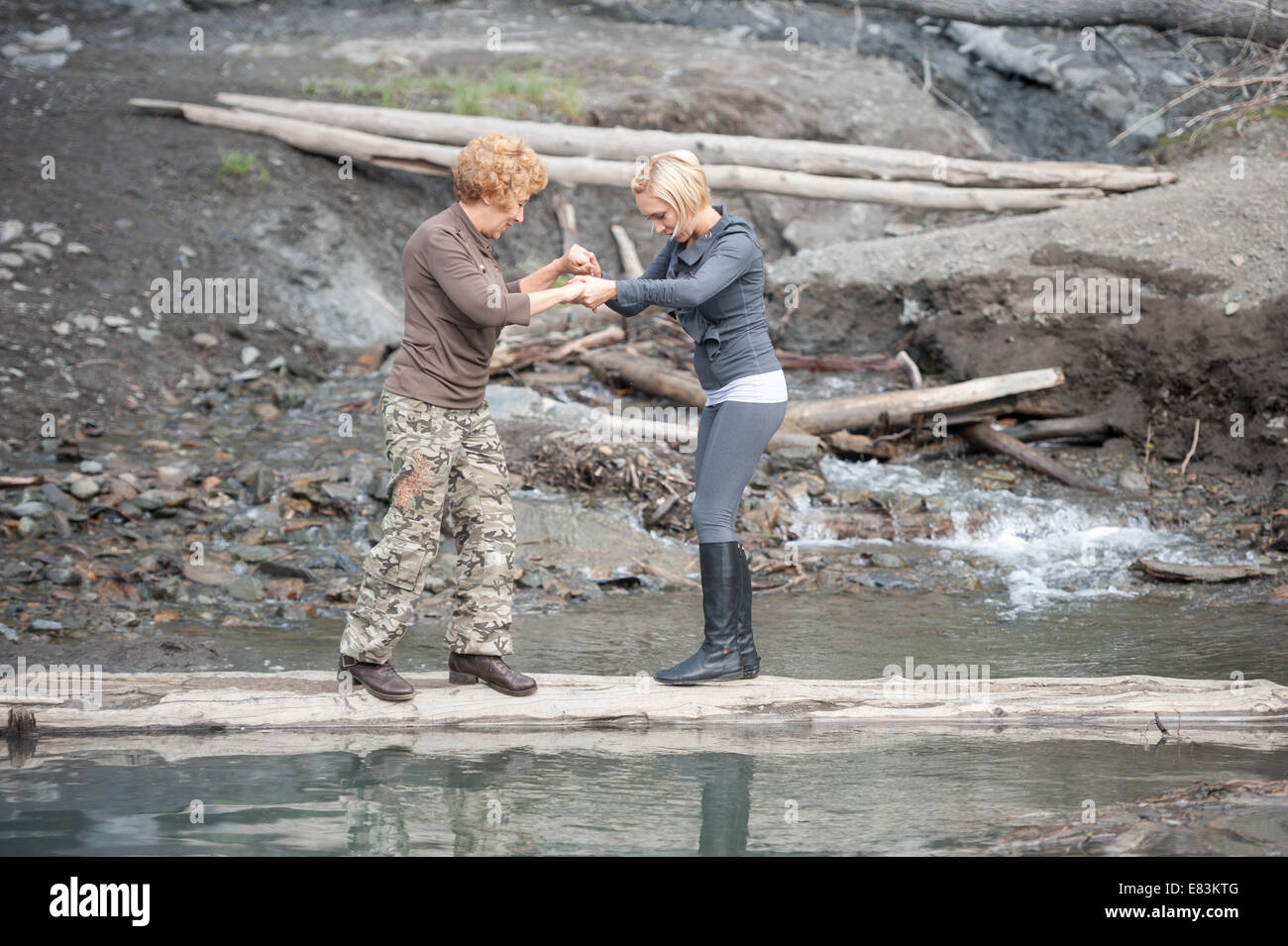 Mother and daughter crossing stream on log in Alaska Stock Photo - Alamy