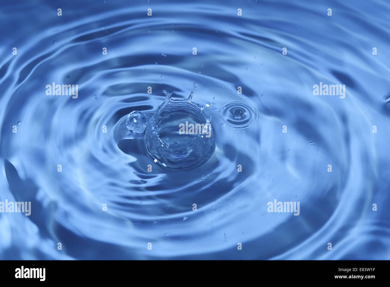 Water splash with a drop of water flying from above Stock Photo - Alamy