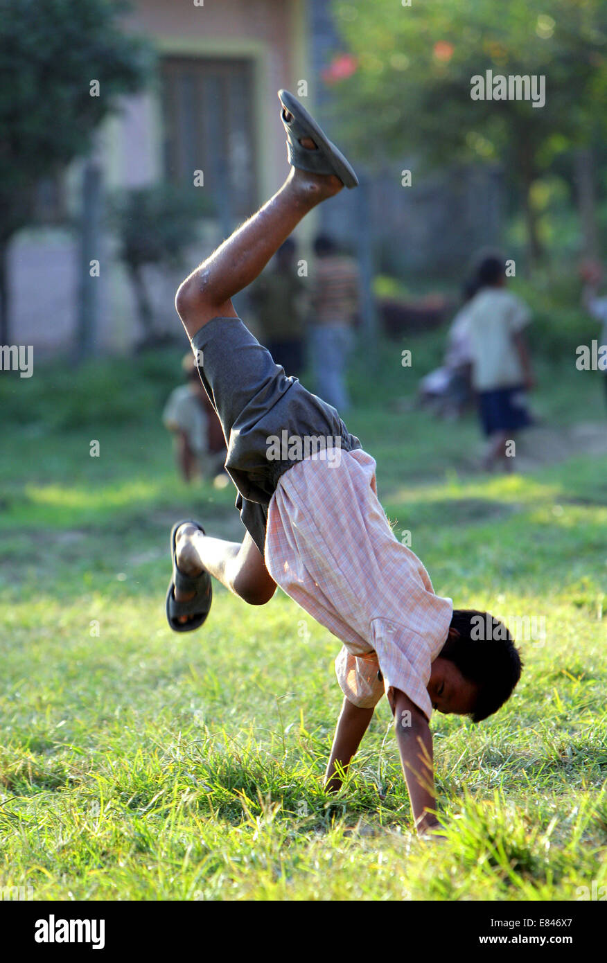 A young boy doing a somersault handstand cartwheels on the grass during ...