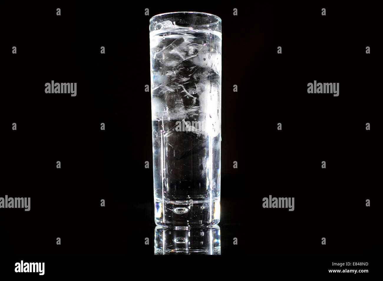 A glass of clear drinking water from a tap against a black background ...