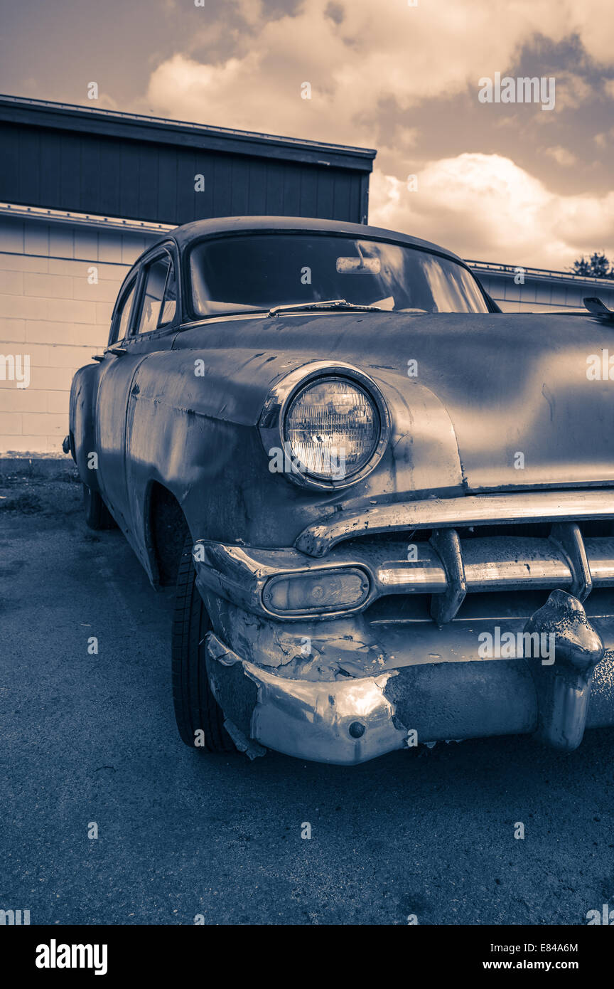 An old junker of a car that has seen better days in front of an garage ...