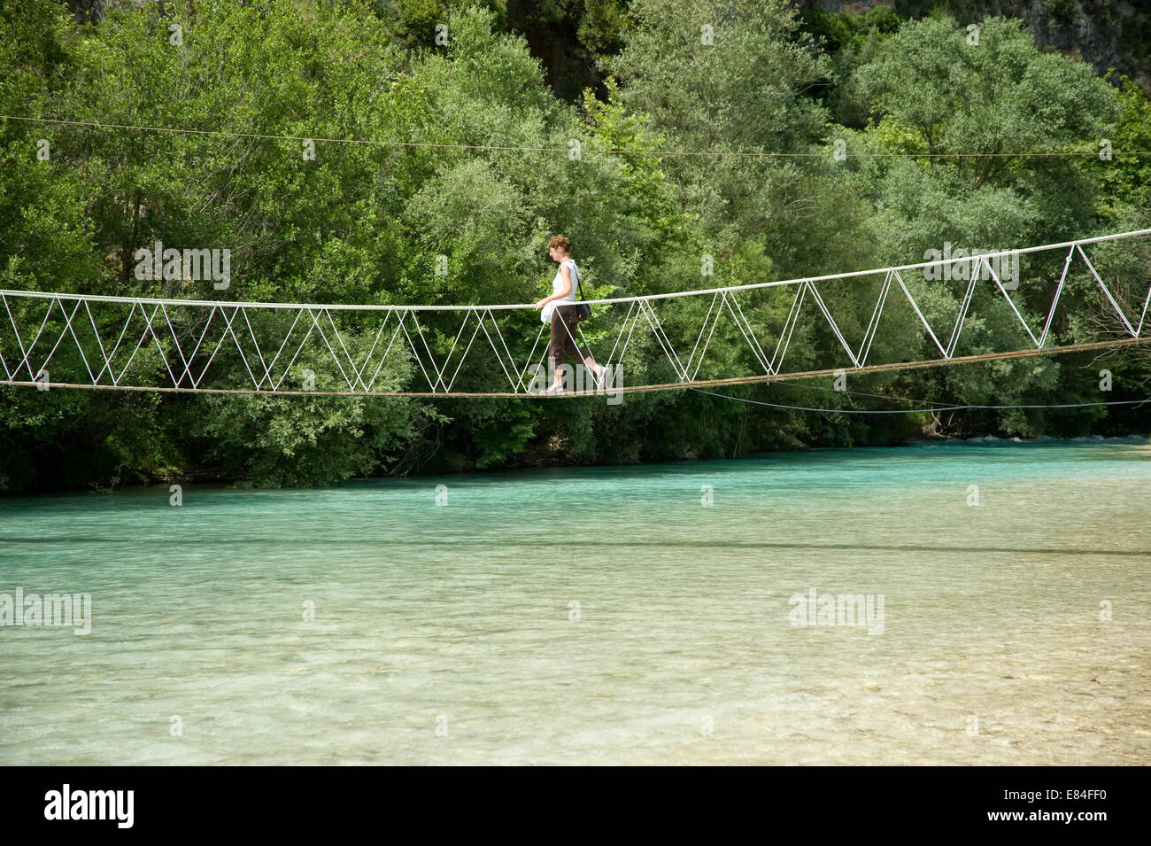 Woman crossing a suspension bridge across the river Acheron in Epiros ...