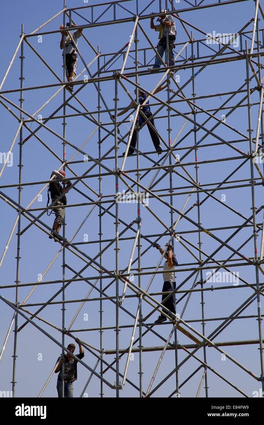 Workers on reinforcing steel rods constructing a huge lighting stand ...