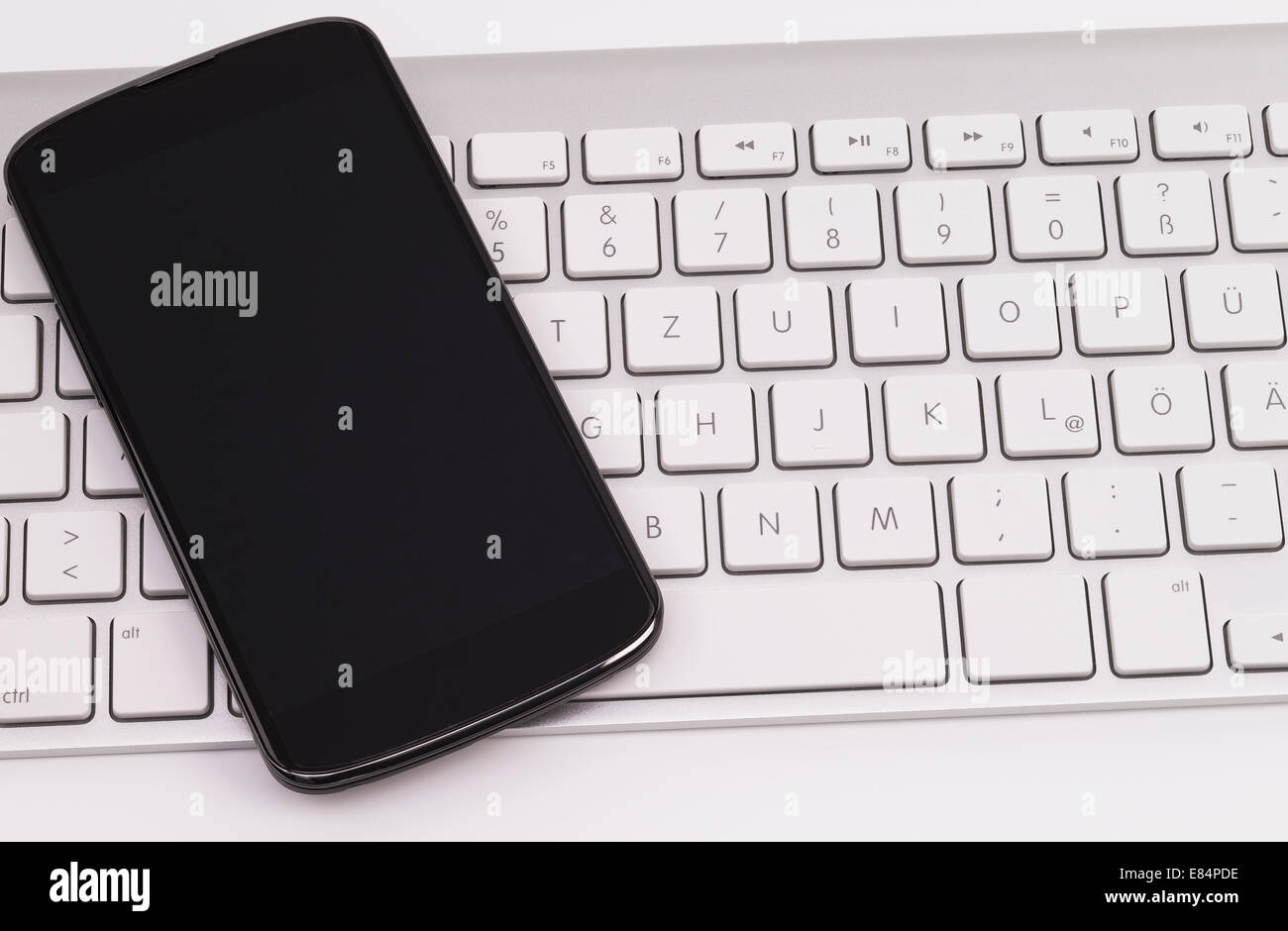 Image shows a smart phone on a keyboard, isolated on white background ...
