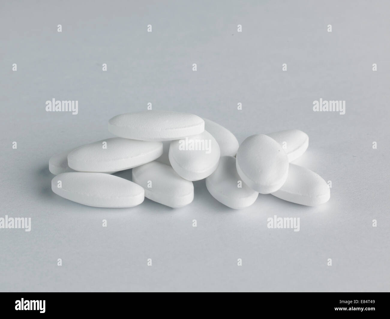 a pile of white lozenge shaped pills on a white background Stock Photo ...