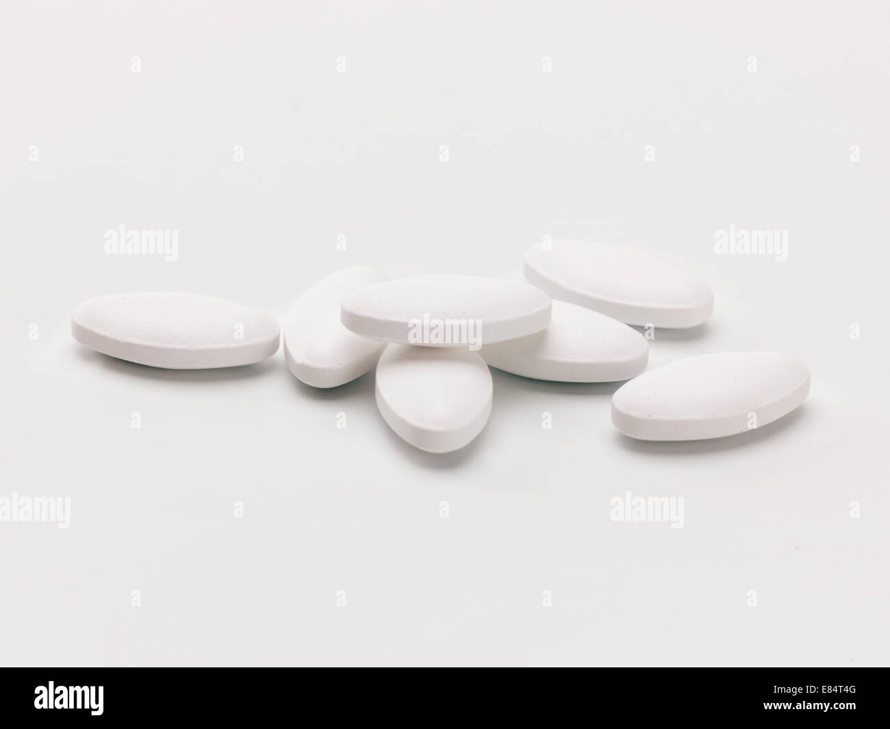 a pile of white lozenge shaped pills on a white background Stock Photo ...