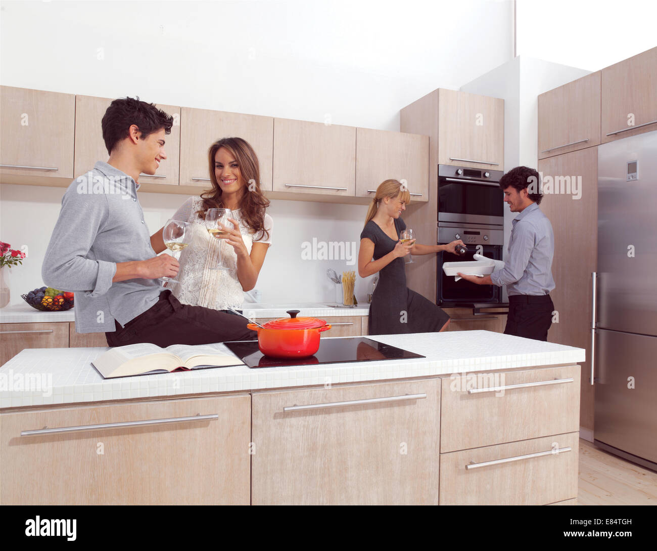 friends preparing pasta standing around the stove cooking spaghetti and ...