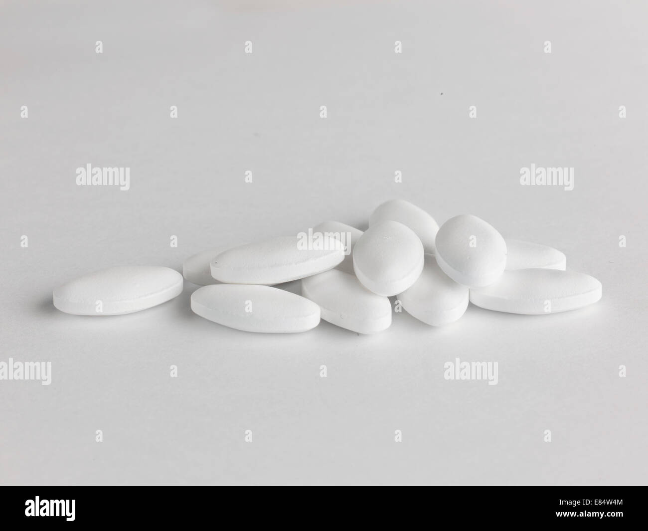 a pile of white lozenge shaped pills on a white background Stock Photo ...