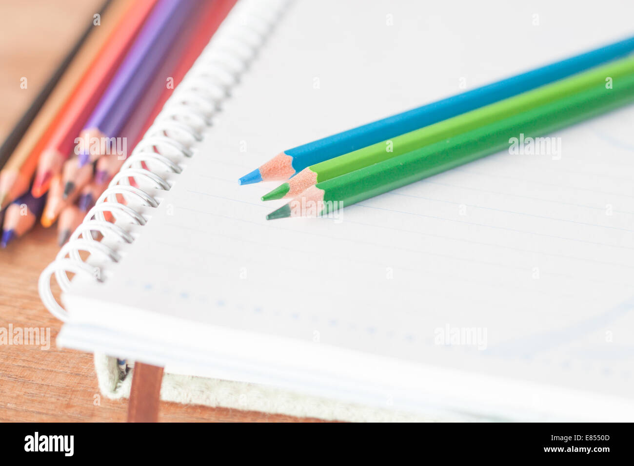 Closeup colorful pencils on spiral notebook and green notebook, stock ...