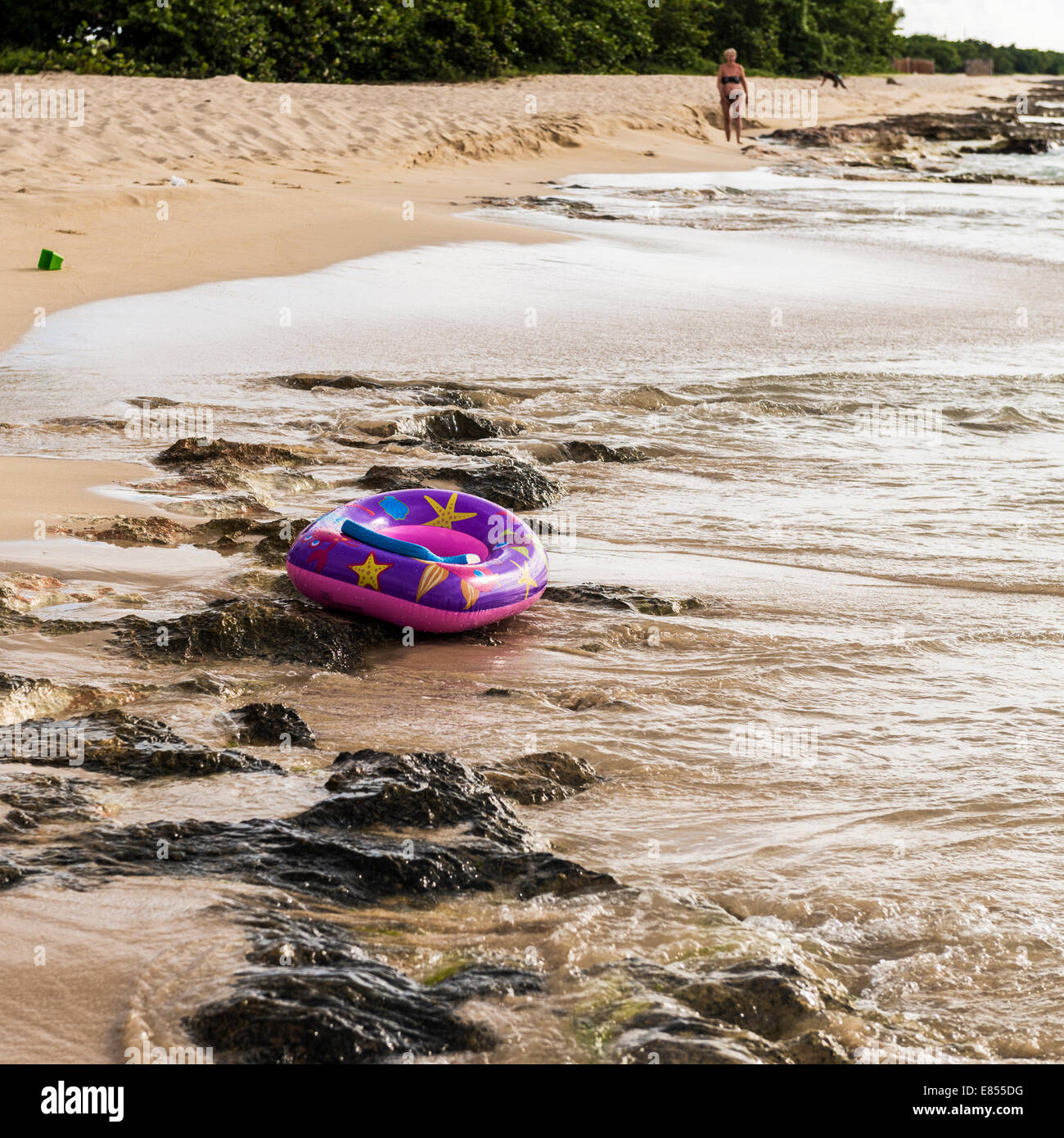 A child's inflatable plastic boat floats free on a tropical beach in St ...