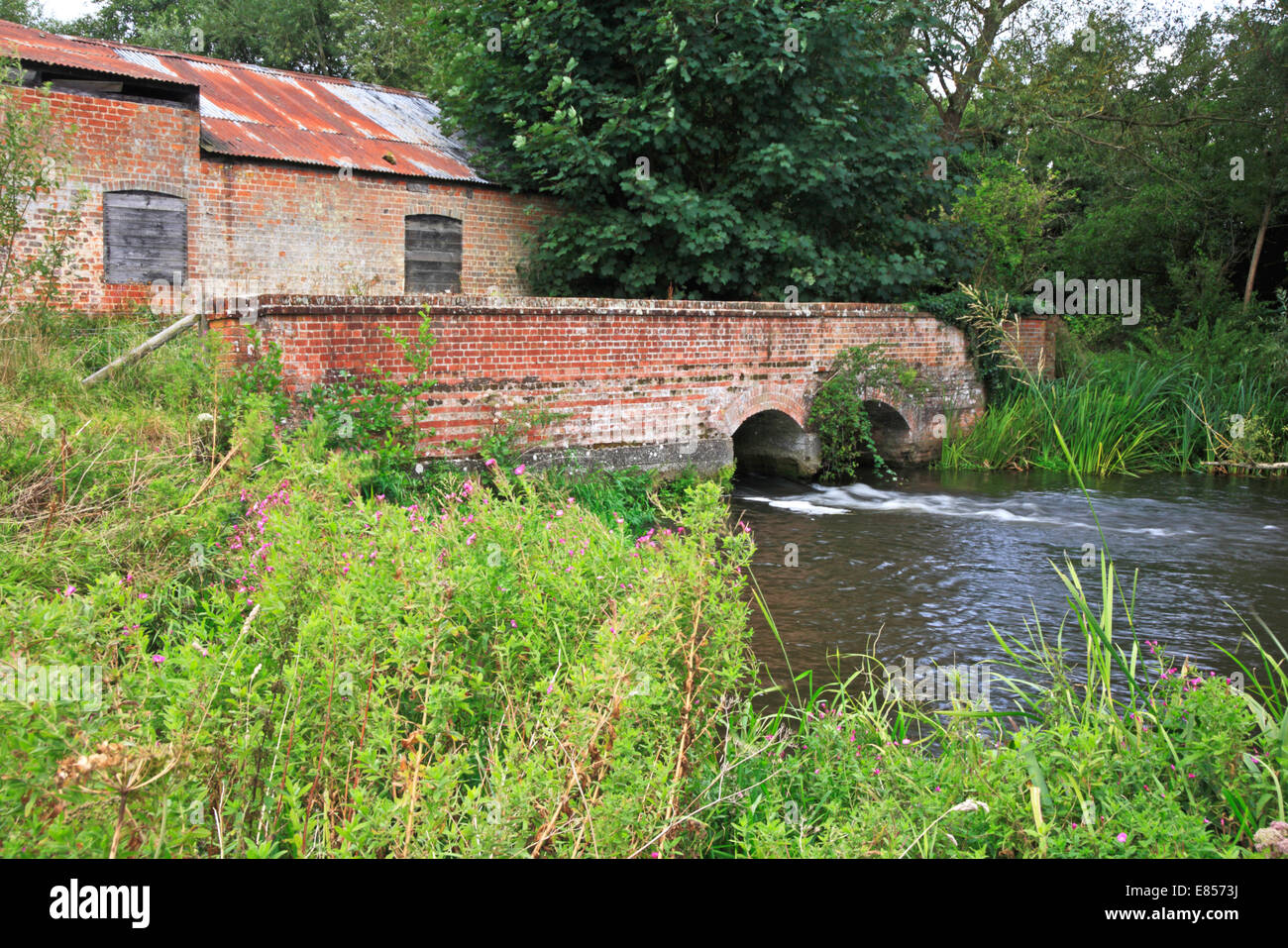 A view of a bridge over the River Bure with the disused mill at ...
