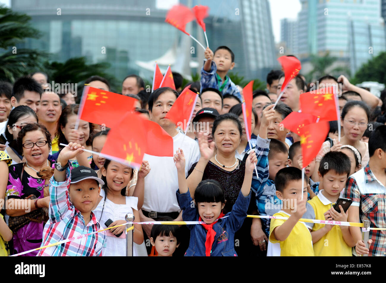 Fuzhou. 1st Oct, 2014. People wave the national flags as they watch a ...