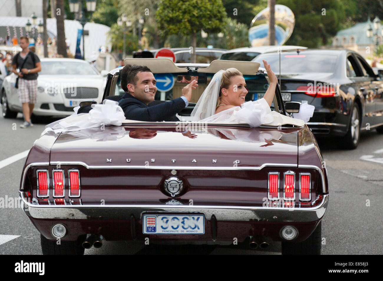 Bride and groom riding in an open Ford Mustang convertible car through ...