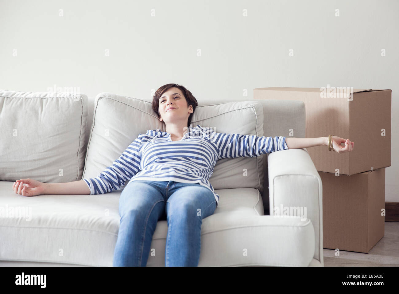 Woman resting on sofa while moving house Stock Photo - Alamy