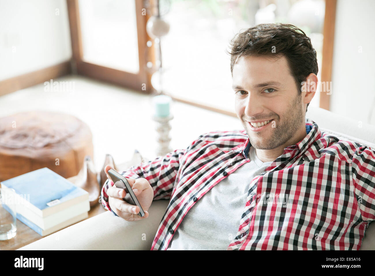 Man using smartphone at home, smiling Stock Photo - Alamy