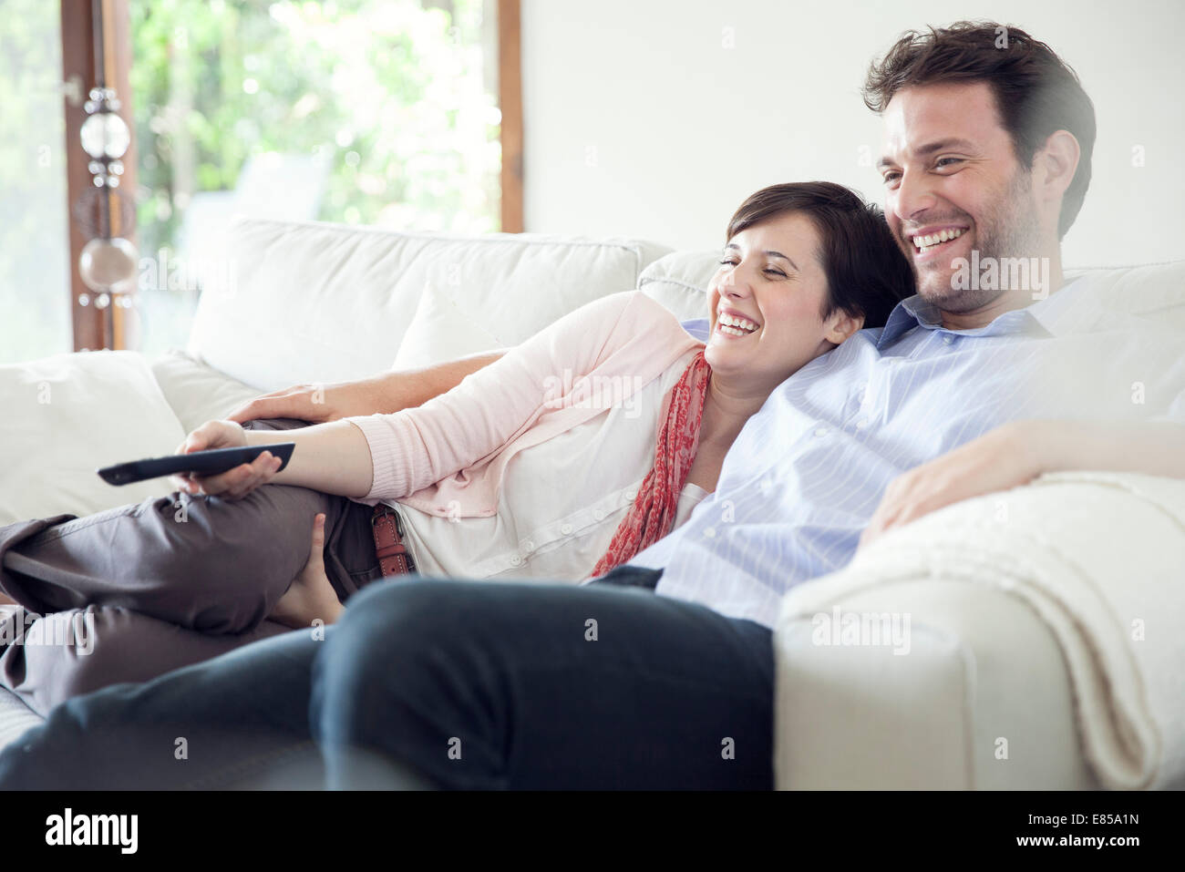 Couple watching TV together on sofa Stock Photo - Alamy