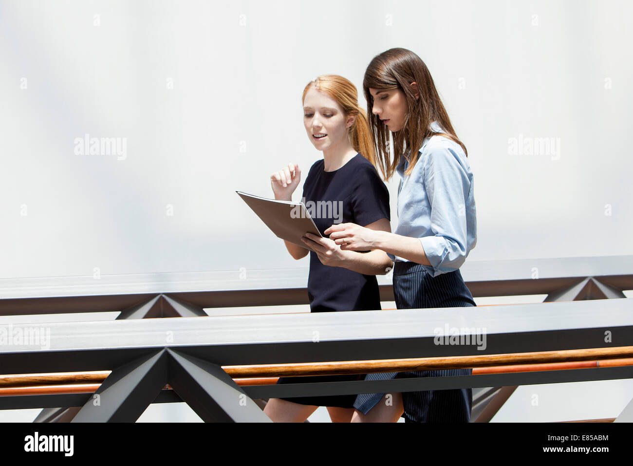 Colleagues walking and discussing file together Stock Photo - Alamy