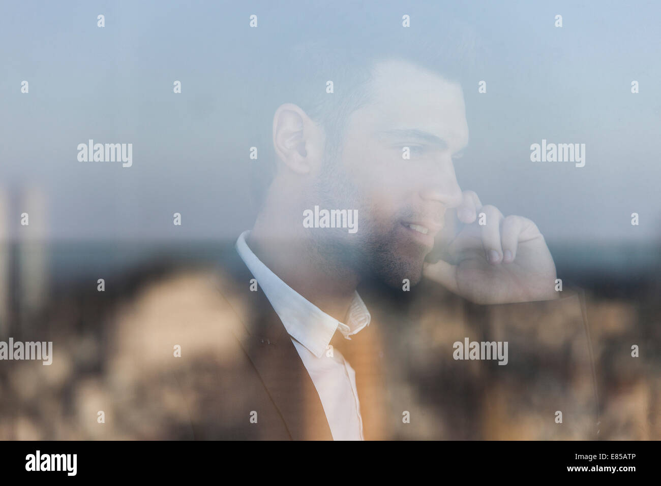 Businessman talking on cell phone, viewed through window Stock Photo ...