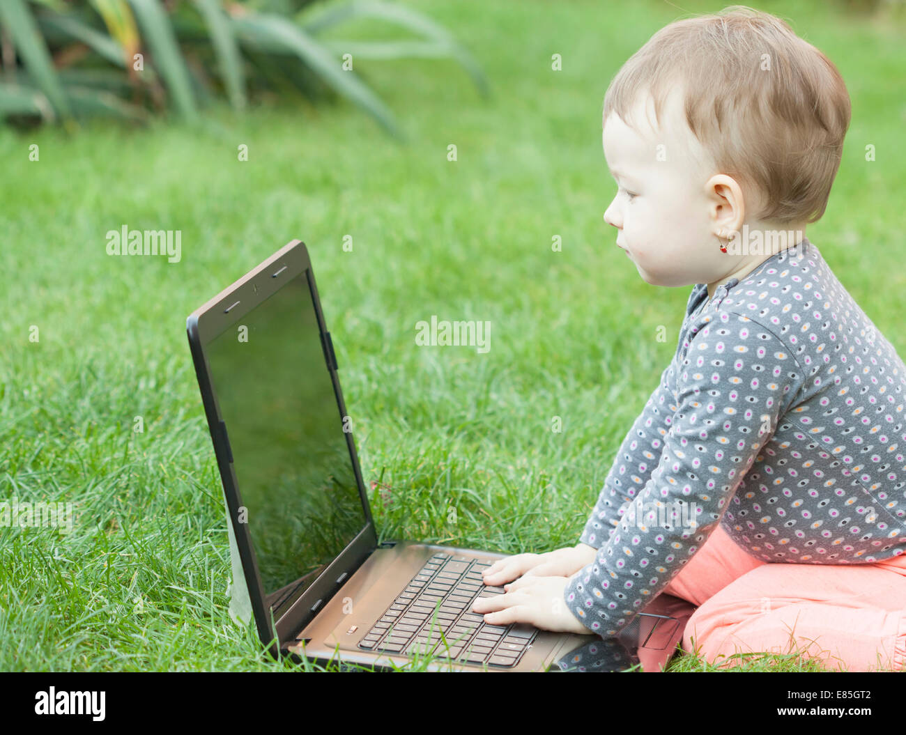Curious baby with laptop computer laying in the grass Stock Photo - Alamy
