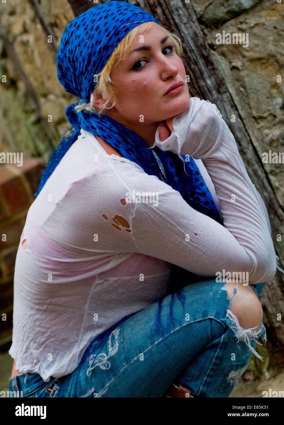 Woman in ripped clothing with blue headscarf Stock Photo - Alamy