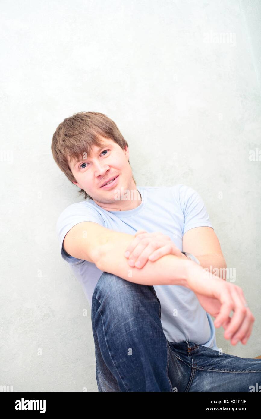 relaxed man sitting on the floor against wall Stock Photo - Alamy