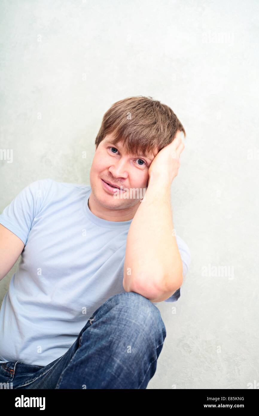 relaxed man sitting on the floor against wall Stock Photo - Alamy