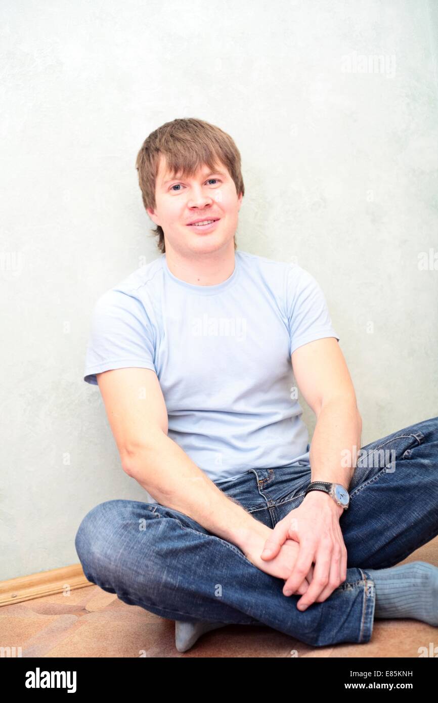 relaxed man sitting on the floor against wall Stock Photo - Alamy