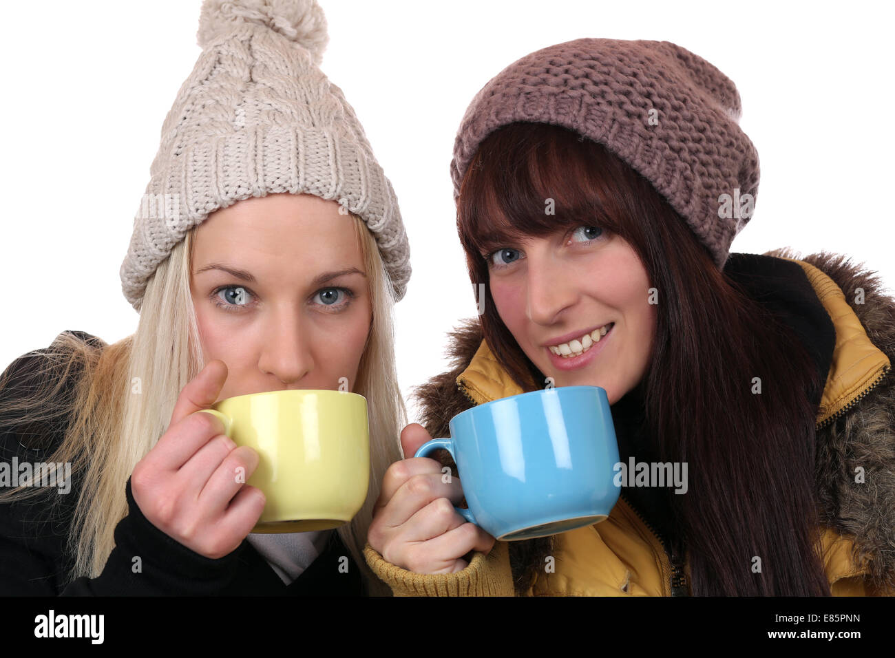 Two young women drinking cup of tea in winter, isolated on a white ...