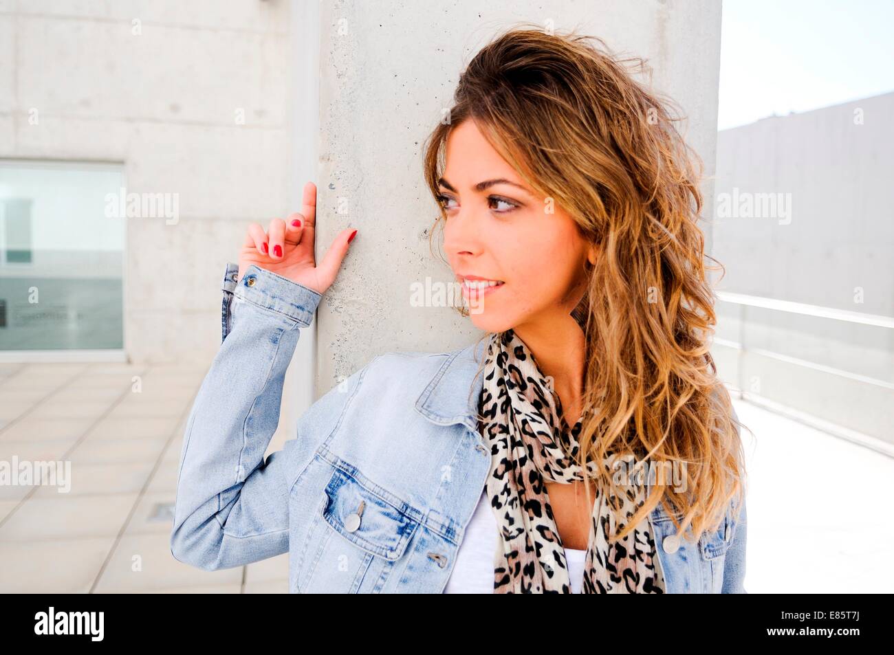 A stylish woman dressed in denim leaning against a wall Stock Photo - Alamy