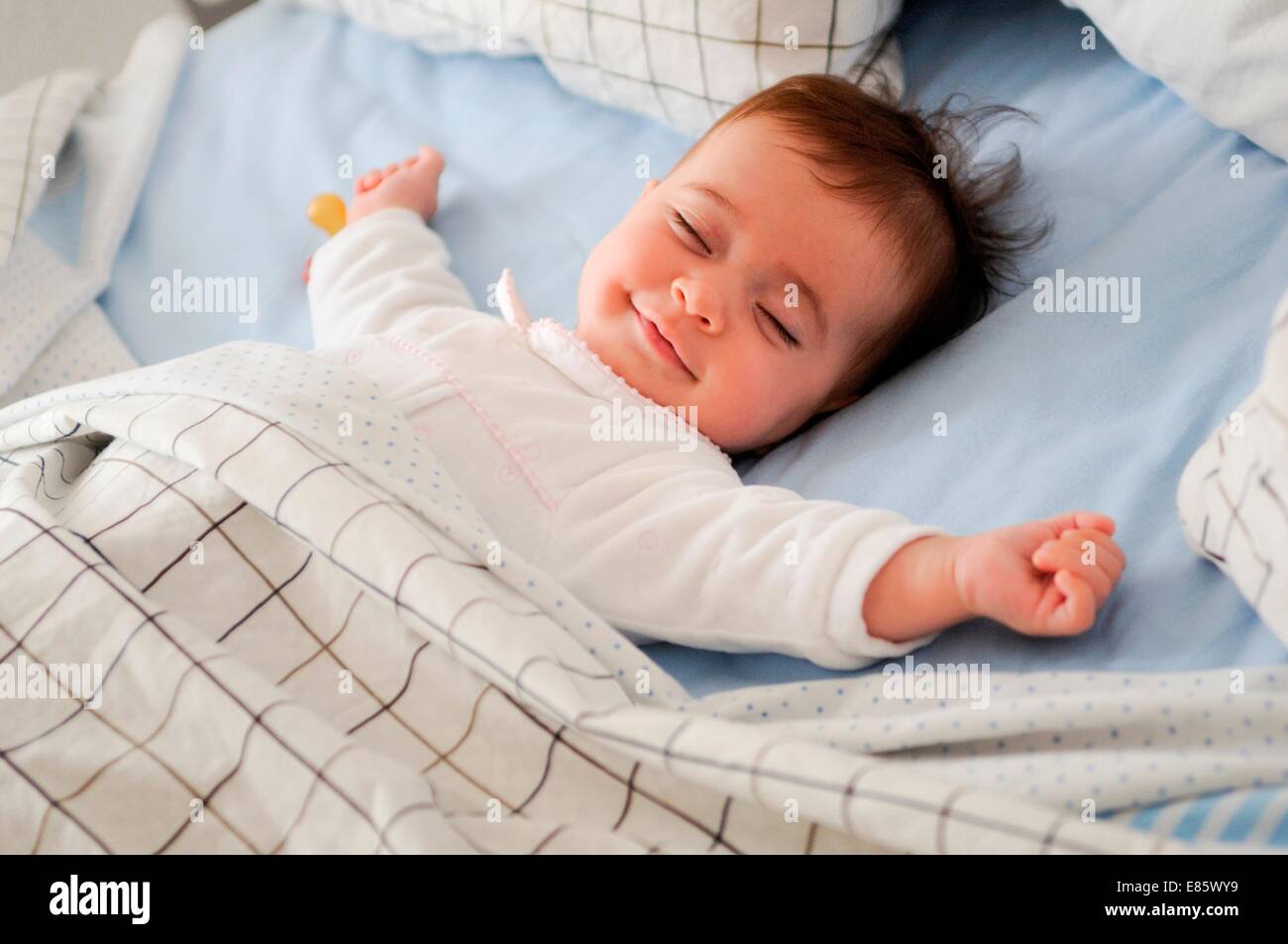 Smiling baby stretching in bed Stock Photo - Alamy