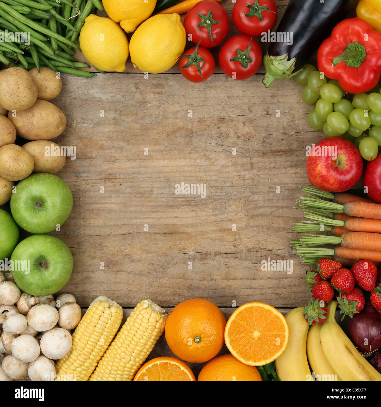 Fresh fruits and vegetables forming a frame on a wooden board with ...