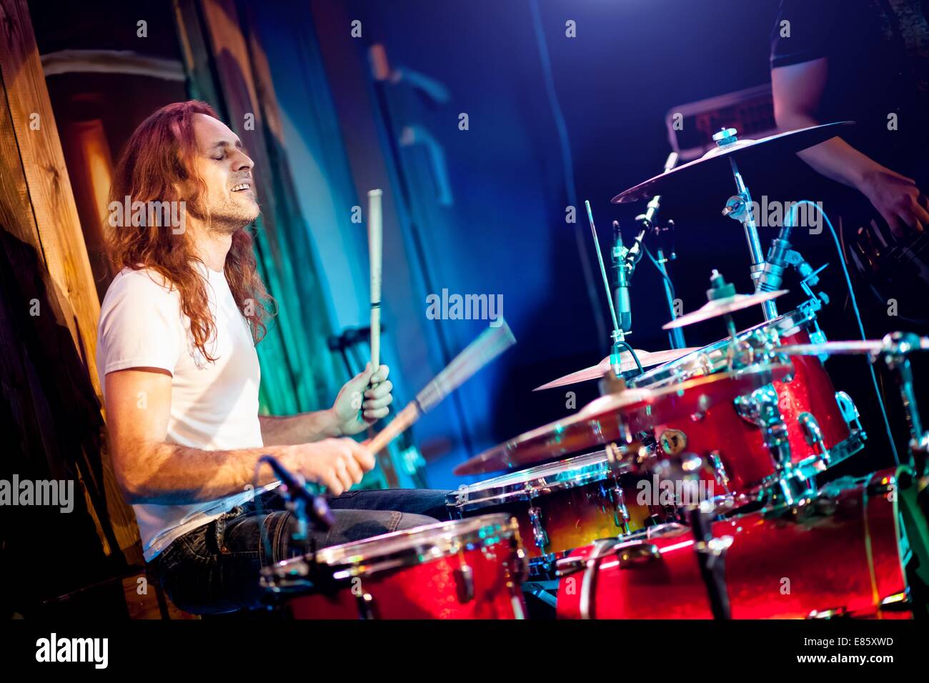musician playing drums on a red background Stock Photo - Alamy
