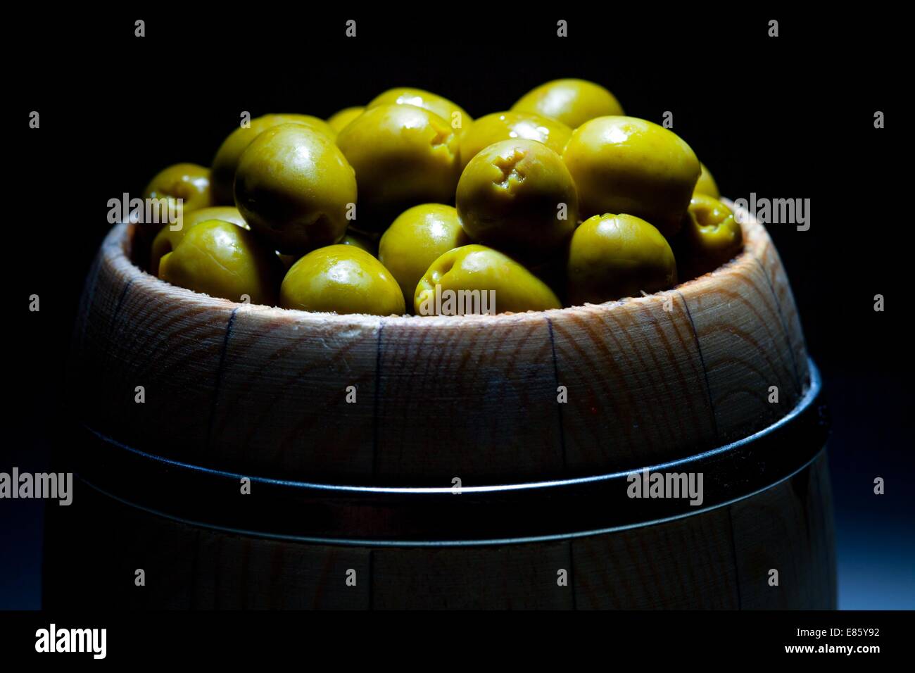 olive in small barrel on a black background Stock Photo - Alamy