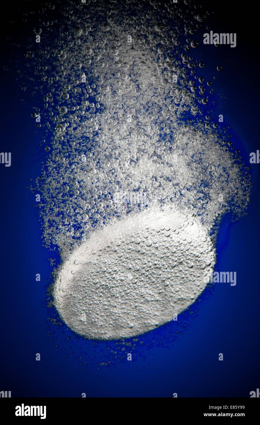 Effervescent tablet in water with bubbles on a blue background Stock ...