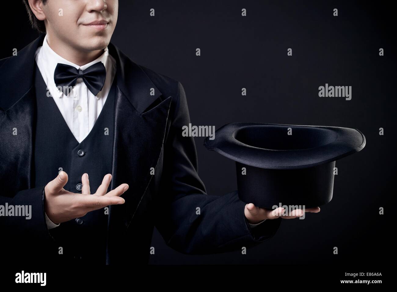 closeup of magician showing tricks with top hat isolated on dark ...