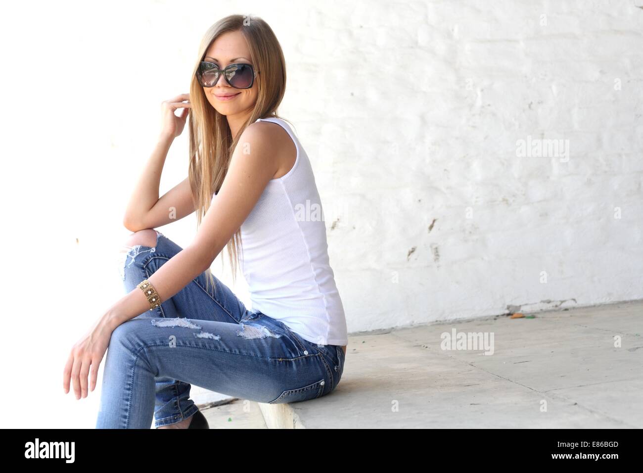 Outdoor photo of pretty girl sitting on the floor in grungy setting ...