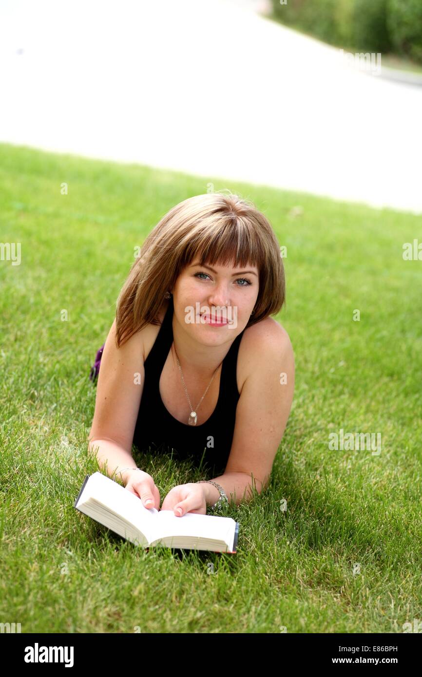 Young happy woman looking at the camera while reading a book in the ...