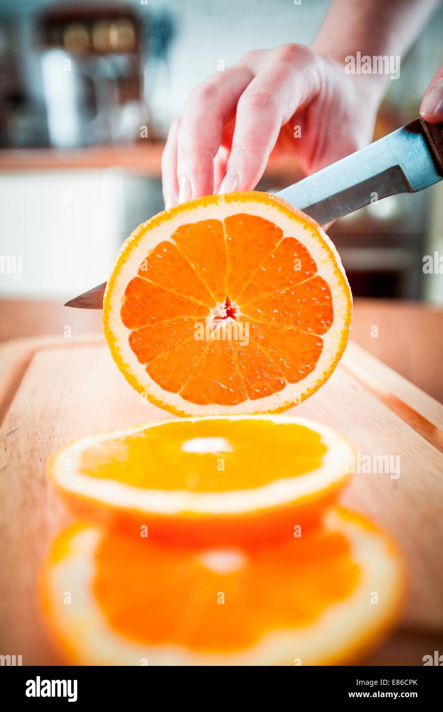 Woman's hands cutting fresh orange on kitchen Stock Photo - Alamy