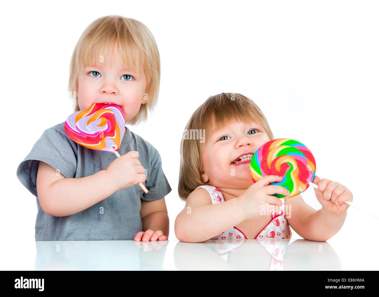 Babies eating a sticky lollipop on white background Stock Photo - Alamy