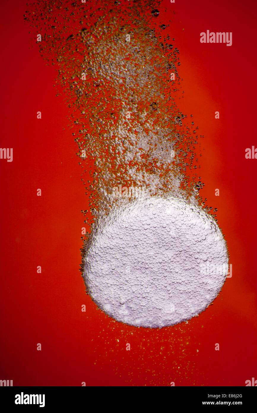 Effervescent tablet in water with bubbles on a red background Stock ...