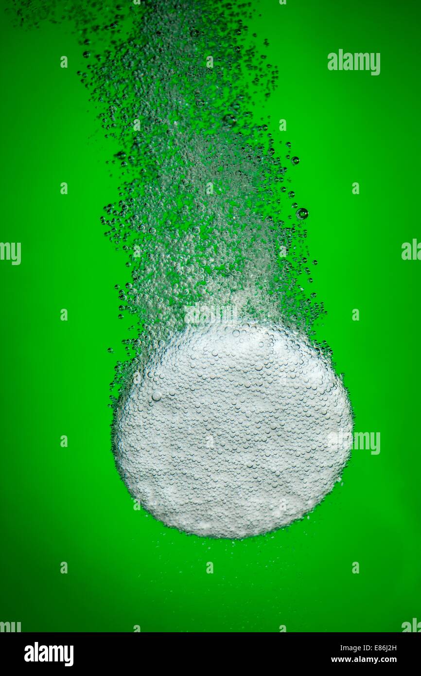 Effervescent tablet in water with bubbles on a green background Stock ...