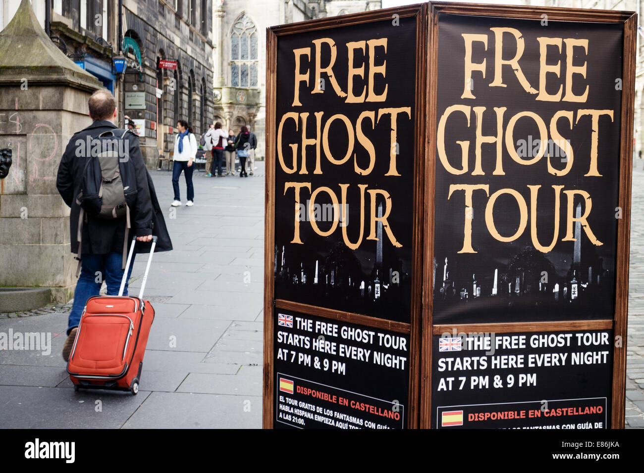 Man with suitcase walking past Edinburgh Ghost Tour placard on the ...