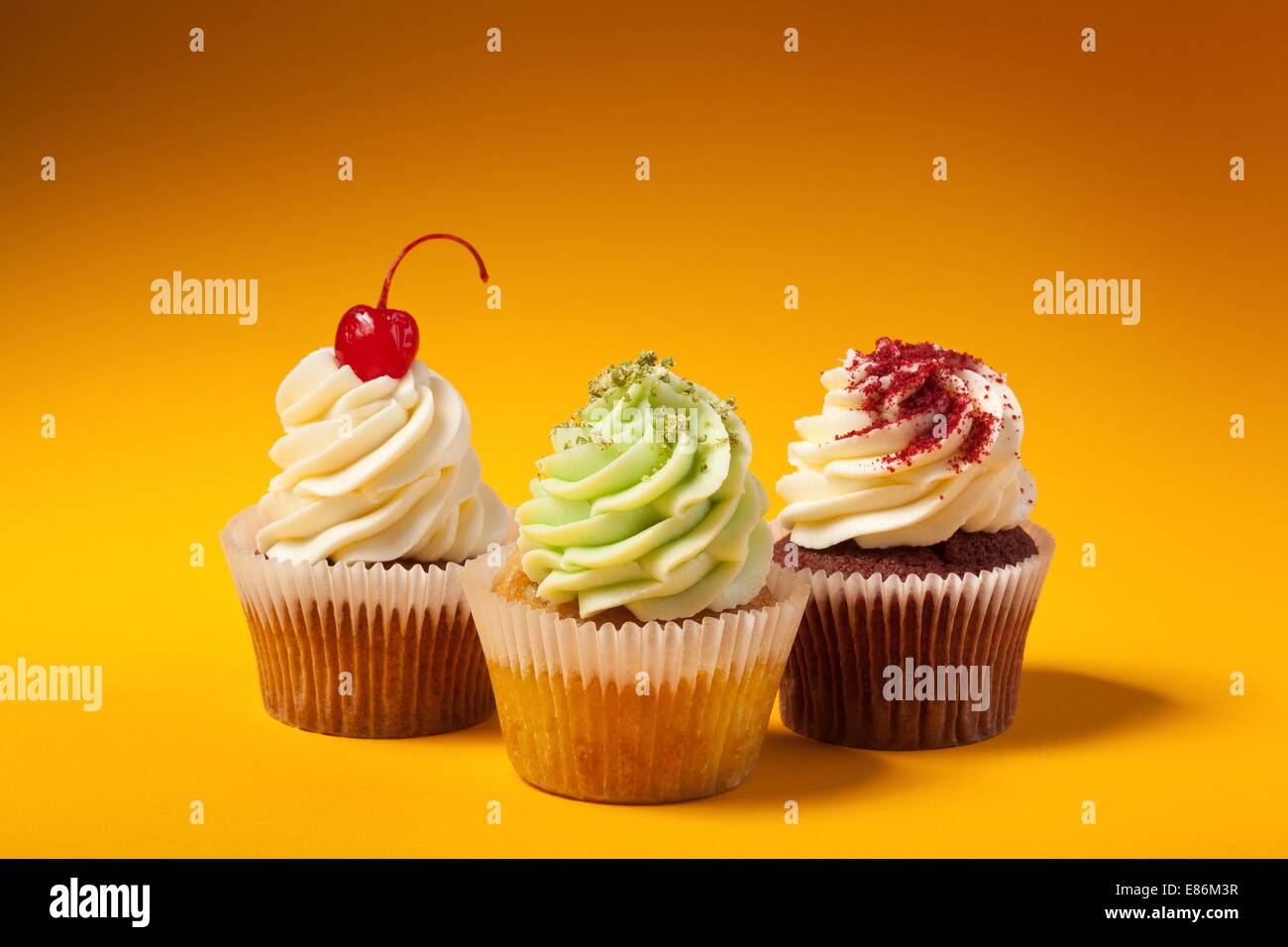 three cupcakes isolated on orange background with copyspace Stock Photo ...